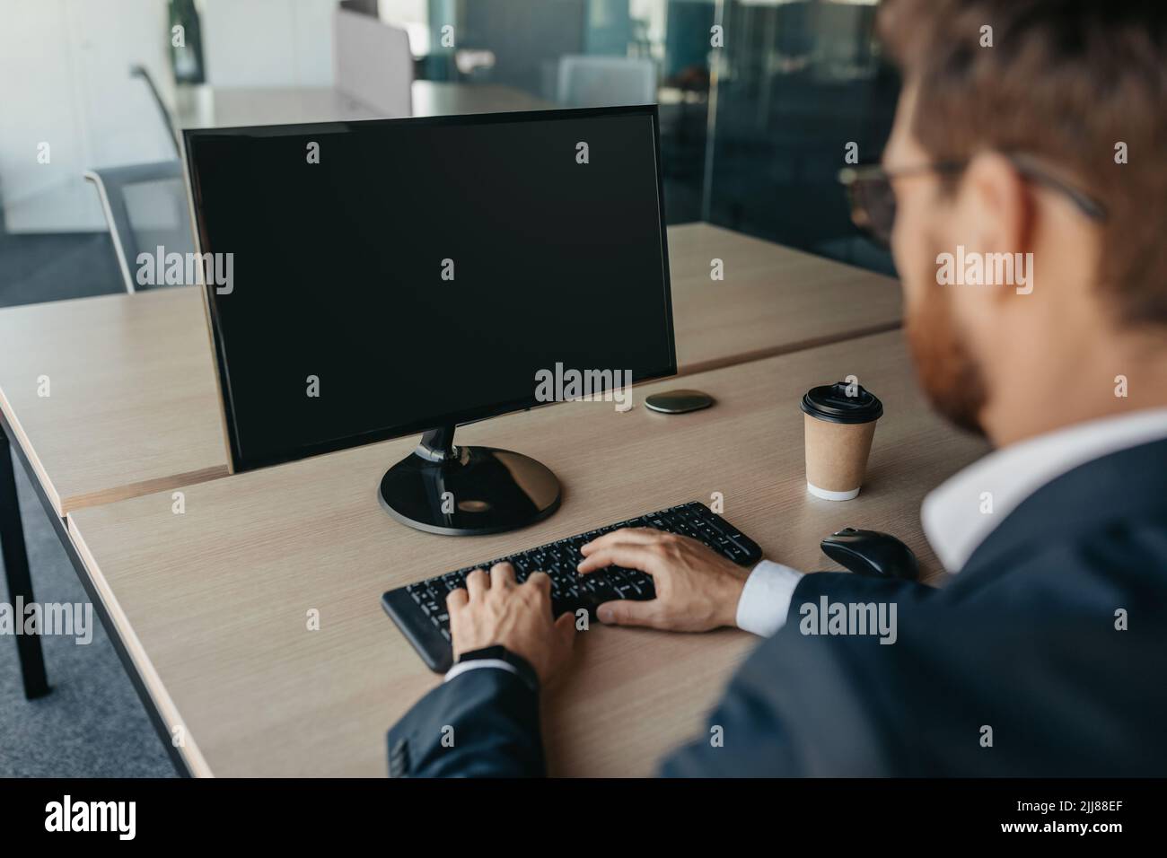 Unrecognizable businessman using computer with empty screen at office, sitting at workplace ...
