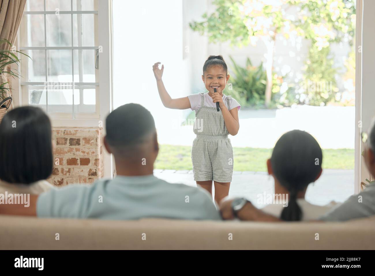 Ta-da. an adorable little girl standing in the living room at home and ...