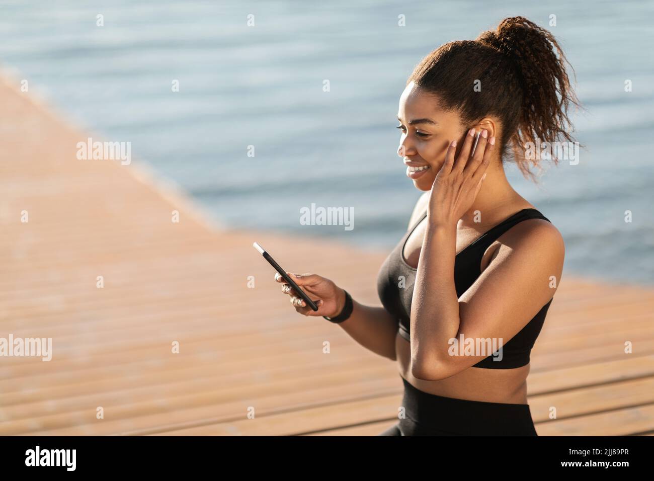 Active african american woman answering phone call while jogging ...