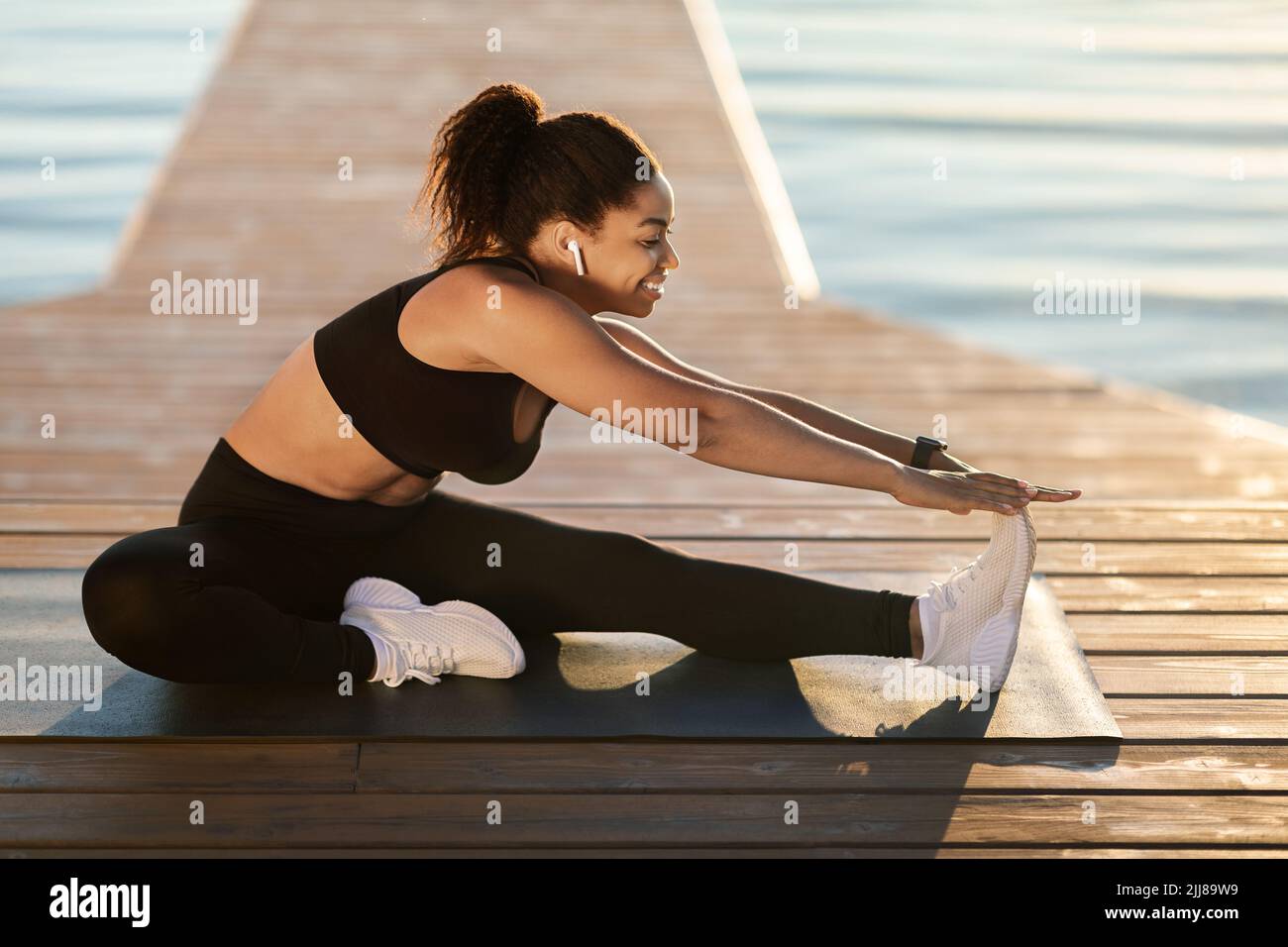 Flexible black woman enjoying stretching workout on the beach Stock ...