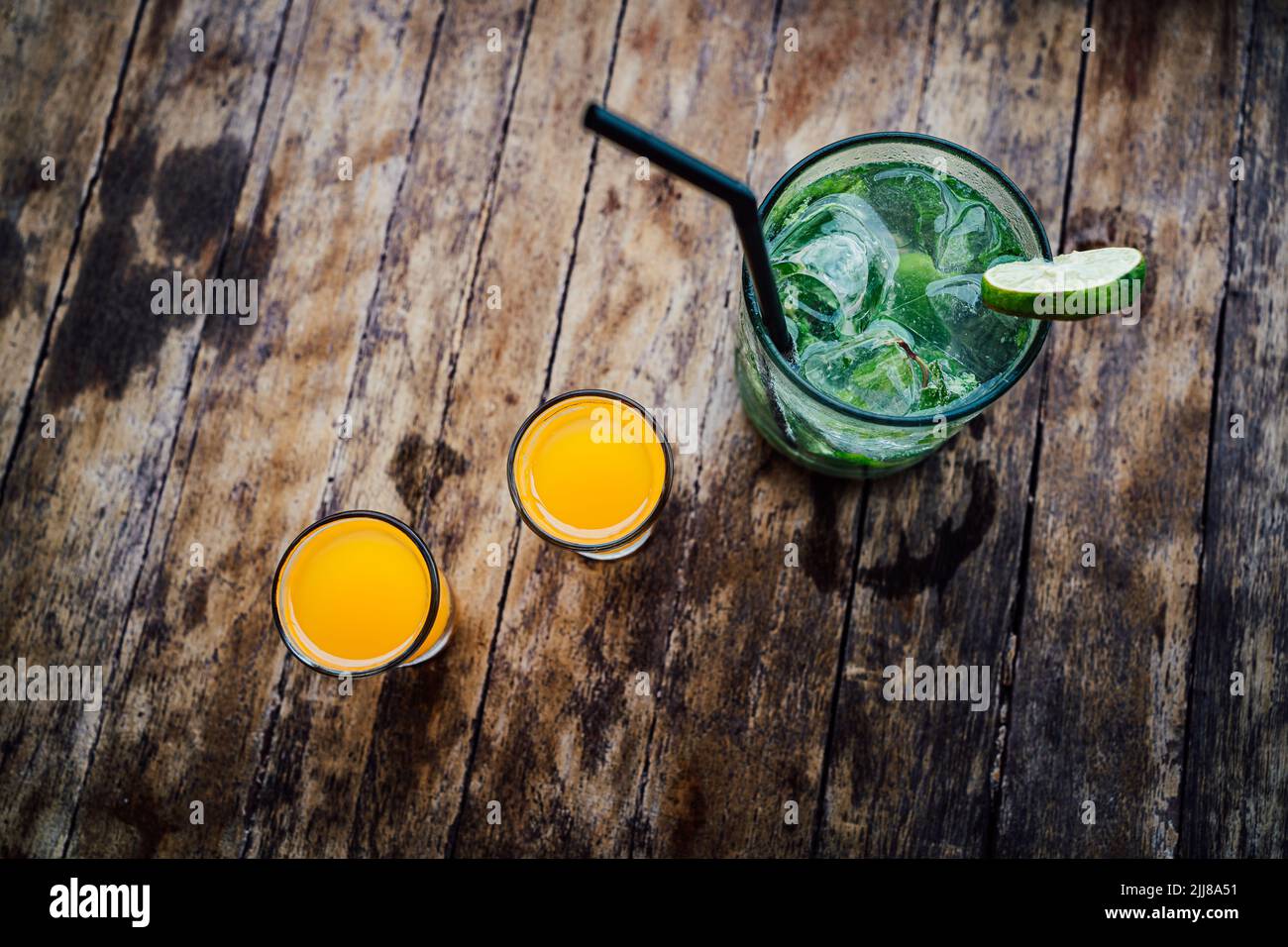 A top view of a mojito with two alcohol shots on the side on a wooden ...