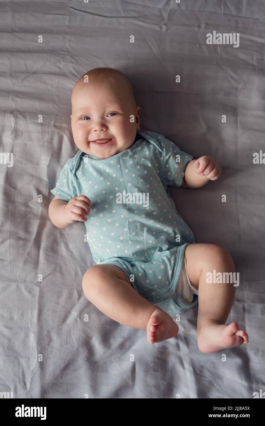 Baby girl in azure clothes with white spots looking at camera with ...