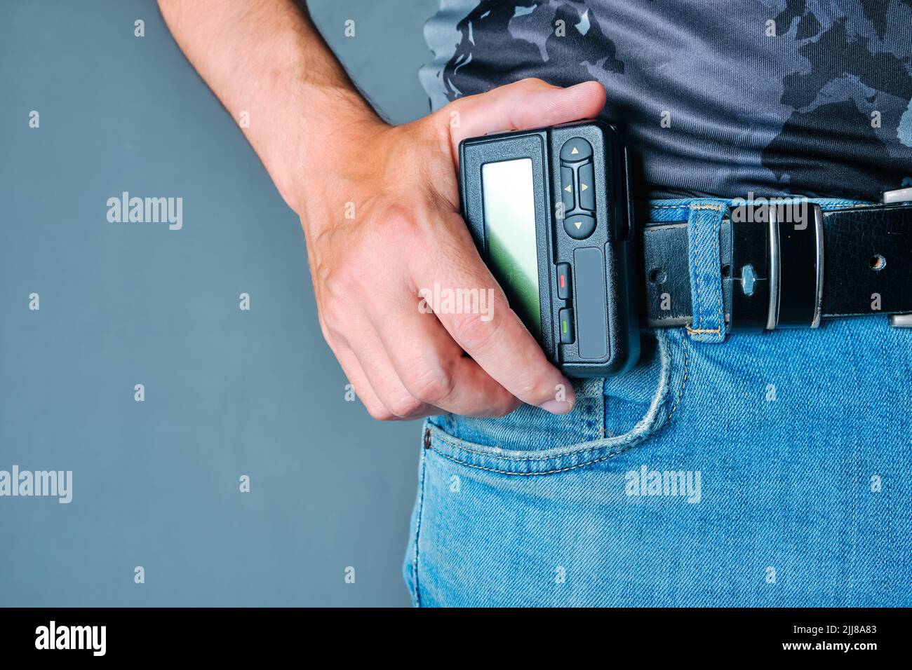 Hand holds pager weighing on belt jeans Stock Photo - Alamy