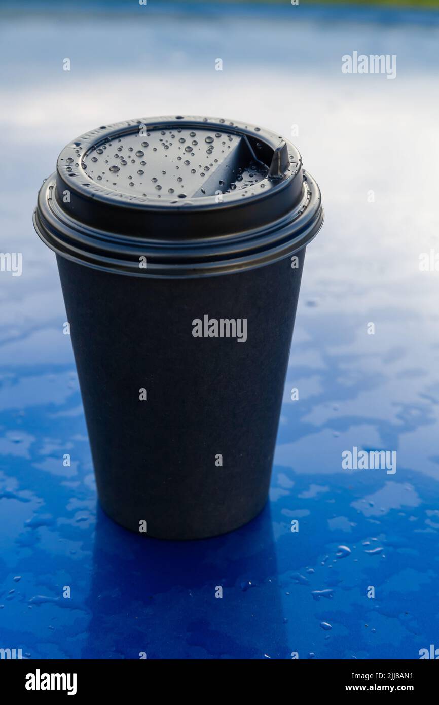 Takeaway paper coffee cups with plastic lids, sleeves on blue ...
