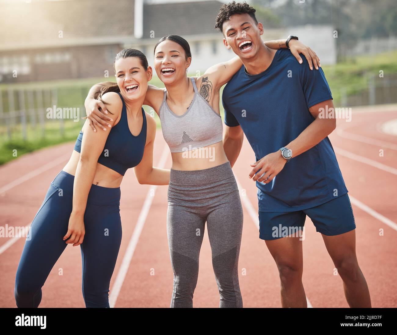 Having a blast out on the track. three young athletes standing outside ...