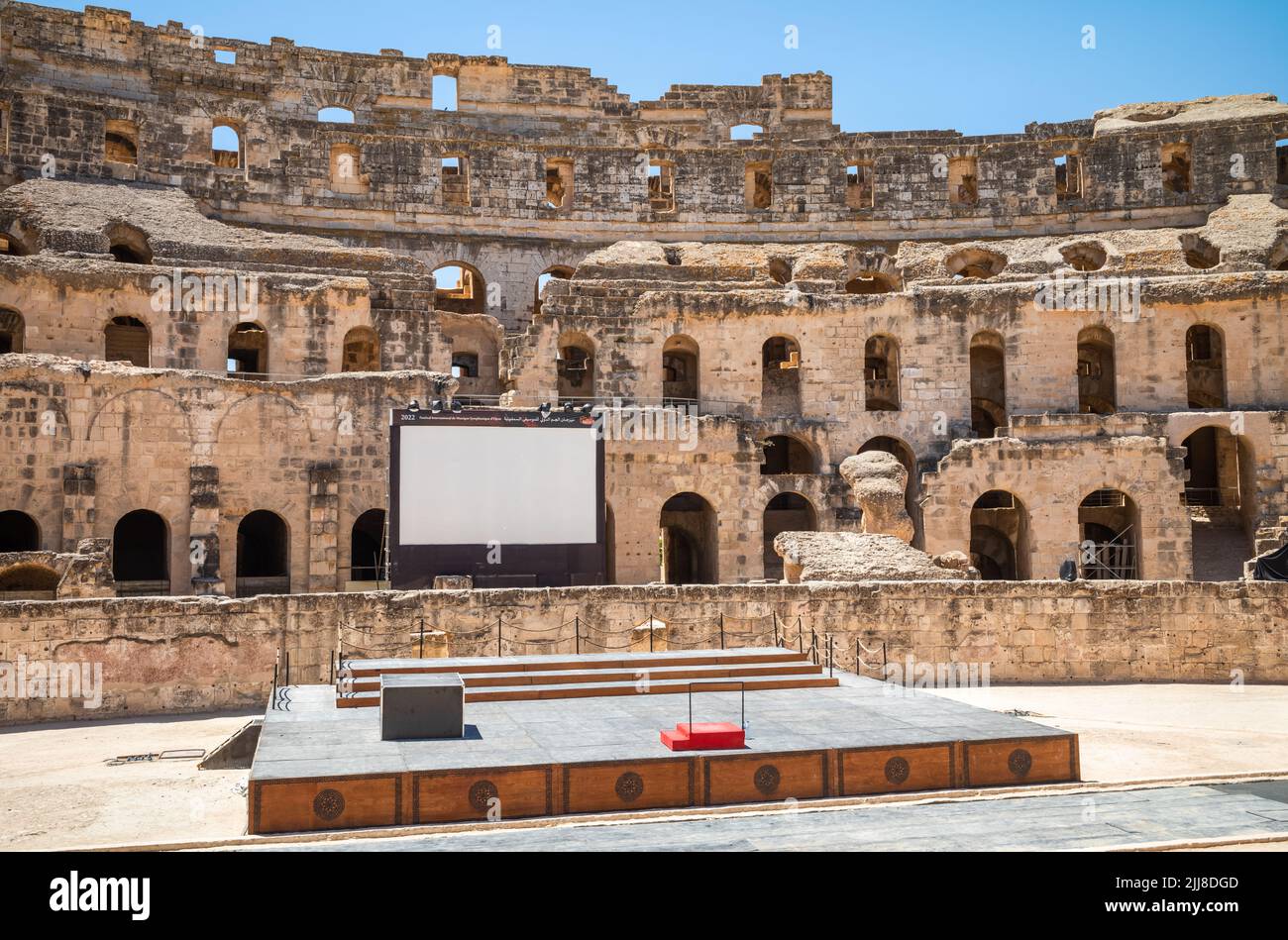 A stage and large screen set up in the arena within the towering ruins ...