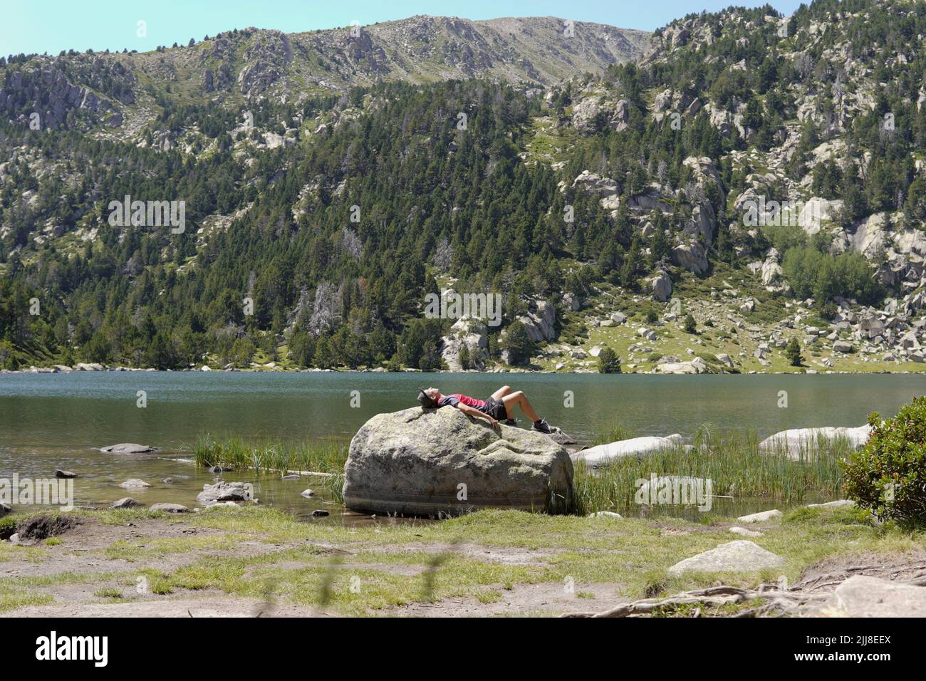 a girl resting on a rock by a lake in the mountains Stock Photo - Alamy