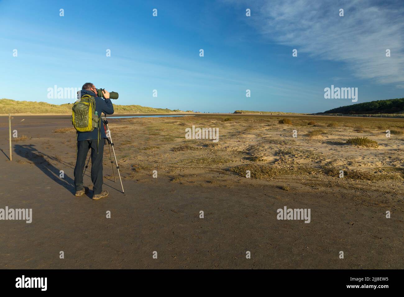 Landscape view of birdwatcher scanning with a telescope, Holkham ...