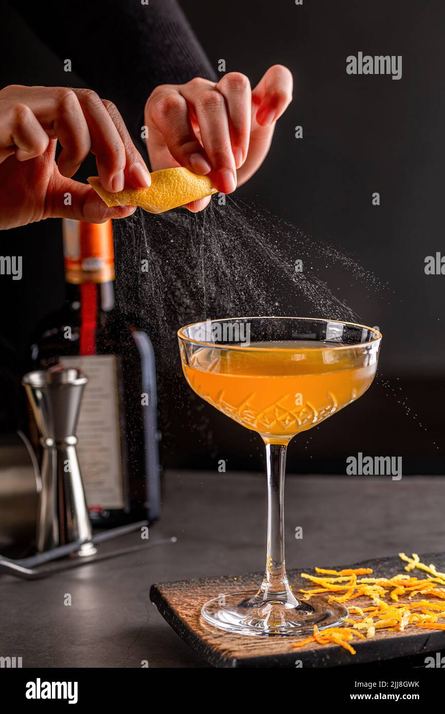 Professional female bartender flavoring a luxury cocktail with ...