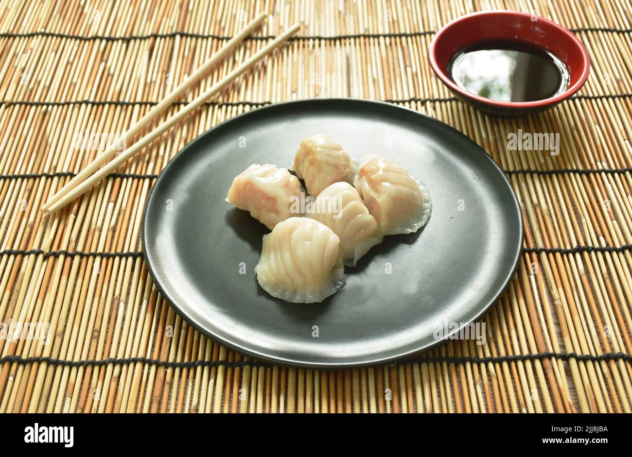 Ha Kao or white dumpling stuffed shrimp and pork on plate dipping soy ...
