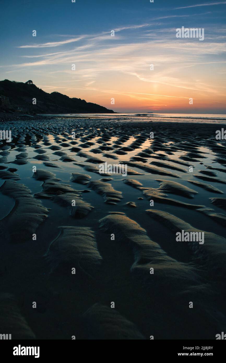 An aesthetic vertical shot of a calm sandy beach in White Cliff Bay ...