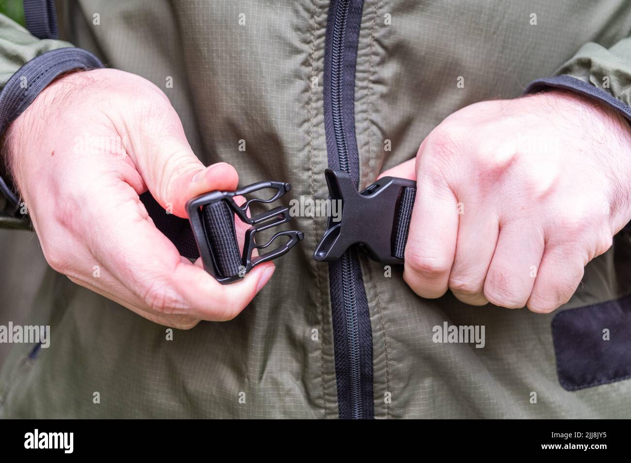 Fasten the waist belt of the backpack. Connect the latch with both ...