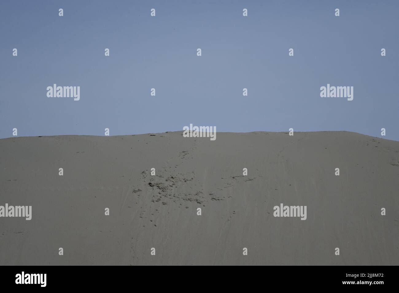 A pile of dry grey sand and cement under blue sky, concept- desert ...