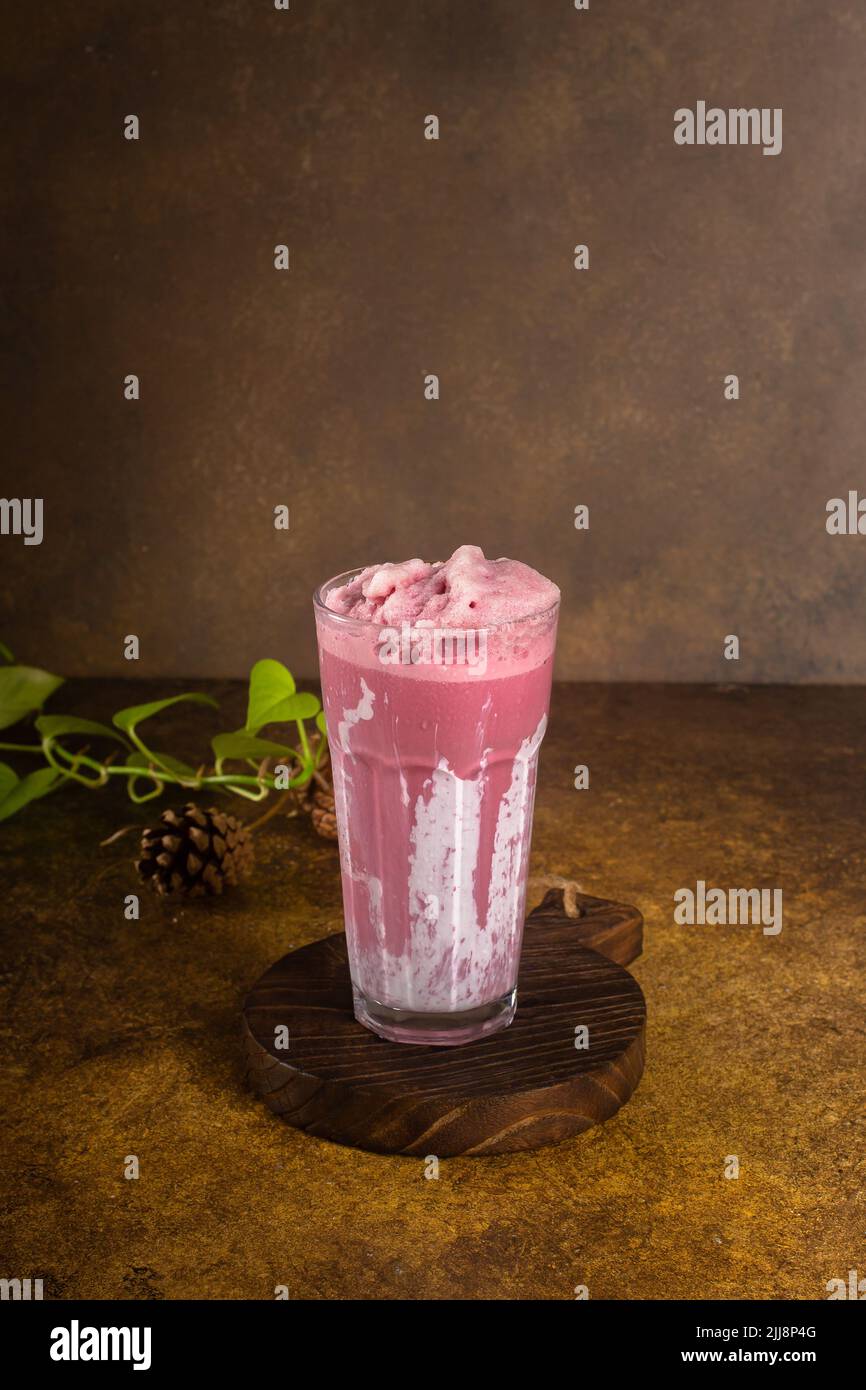 iced taro latte on rustic coaster and with green plants at top of old ...