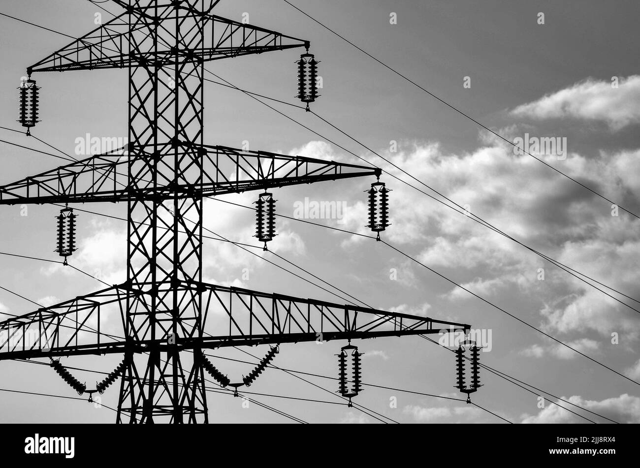 A closeup of a high voltage pylon under a cloudy sky in greyscale Stock ...
