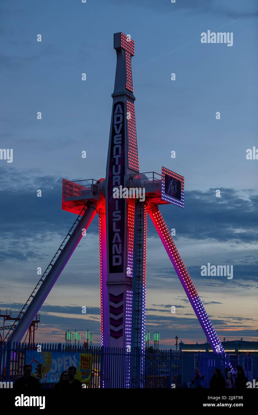 A Pendulum ride lit with multi color light bulbs at sunset. Roller ...
