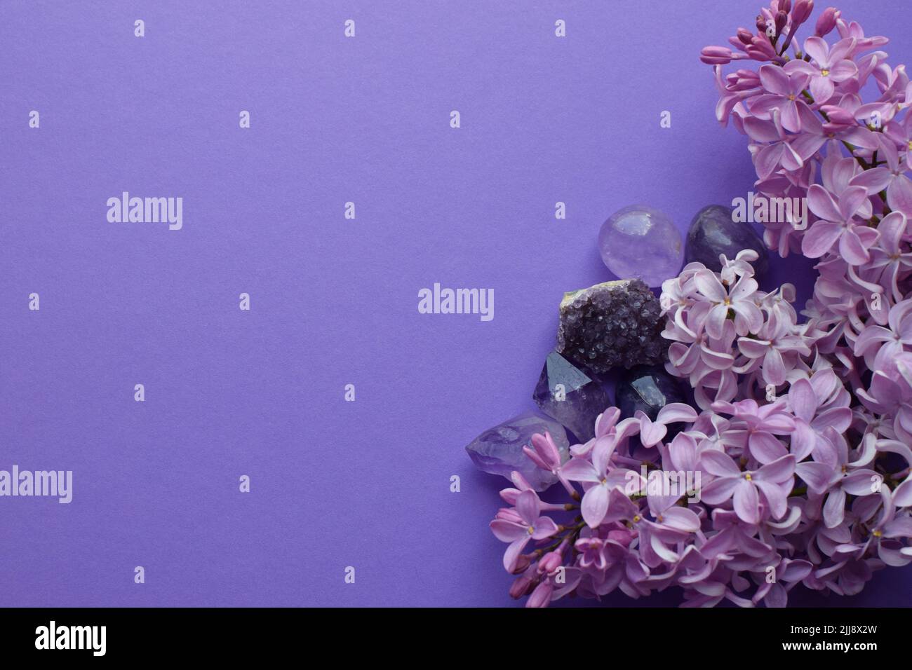 Beautiful lilac flowers and semi-precious stones amethyst lie on a ...