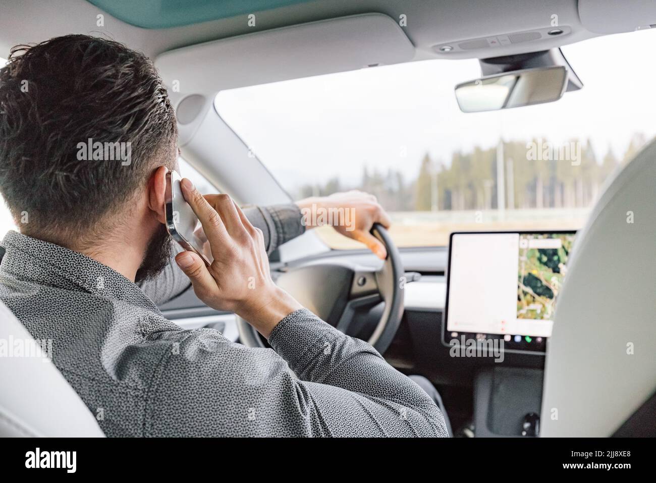Male driver at the wheel of a electric car, driving and talking on ...