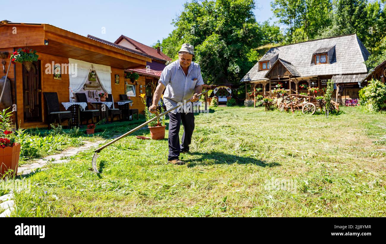 a farmer is cutting gras with a sense in Romania Stock Photo - Alamy