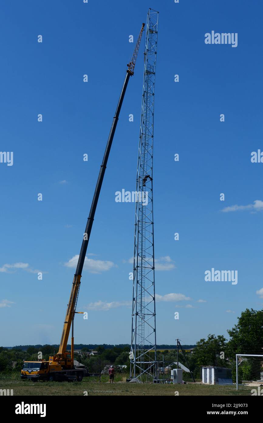 A team of fitters using a crane assembles a metal structure of a ...