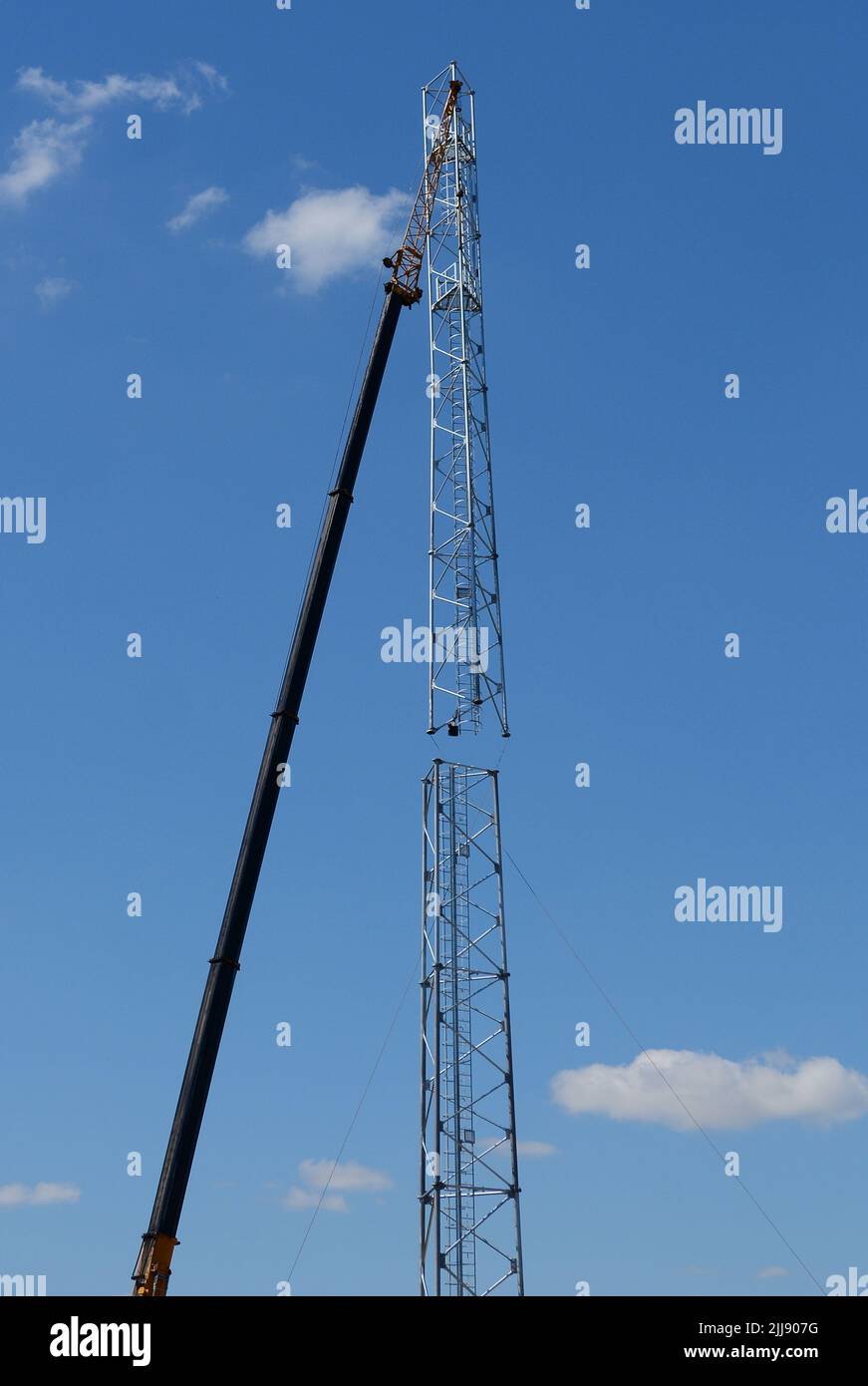 A team of fitters using a crane assembles a metal structure of a ...