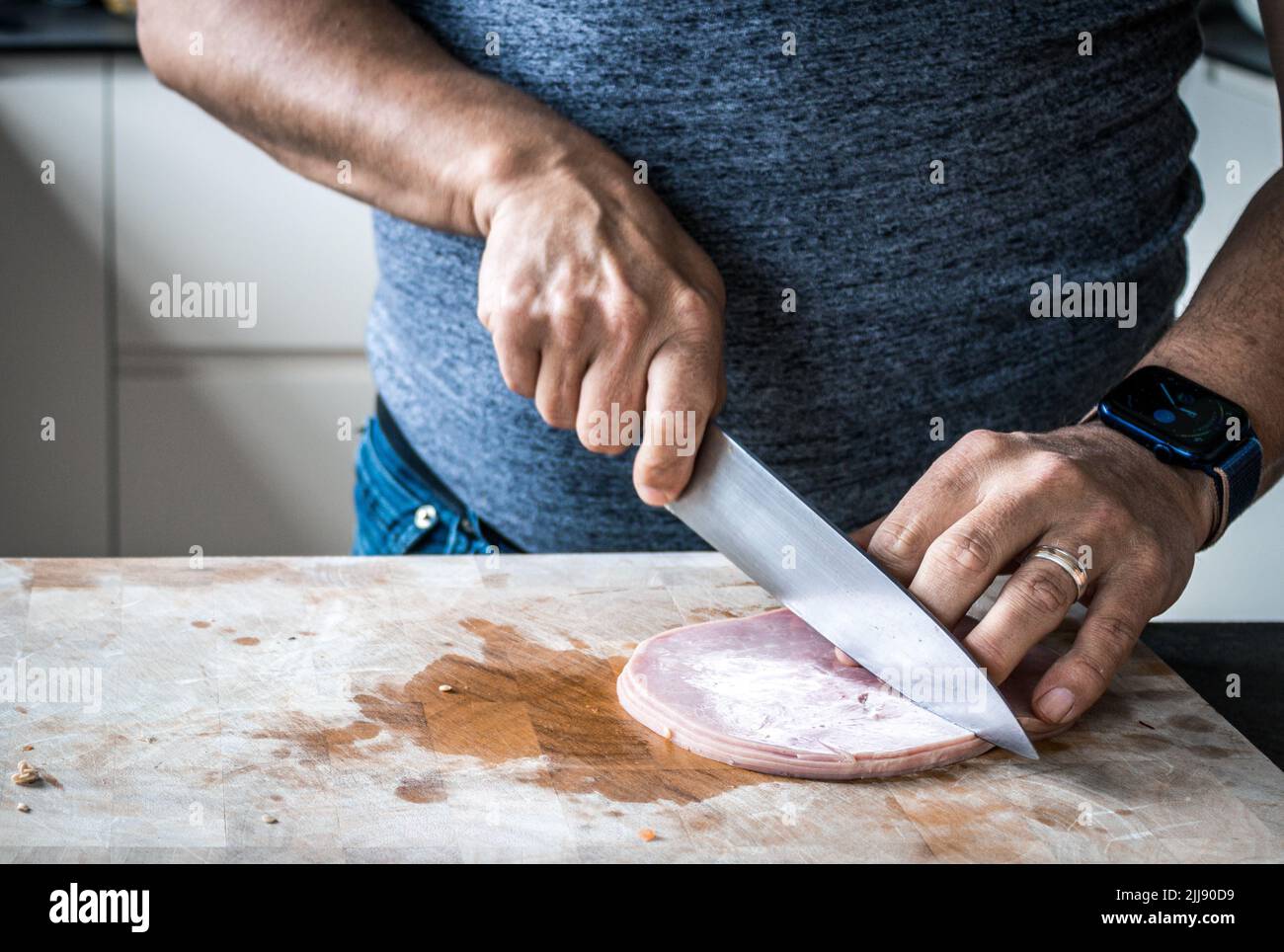 The partial view of a man slicing the ham with a sharp knife in the ...