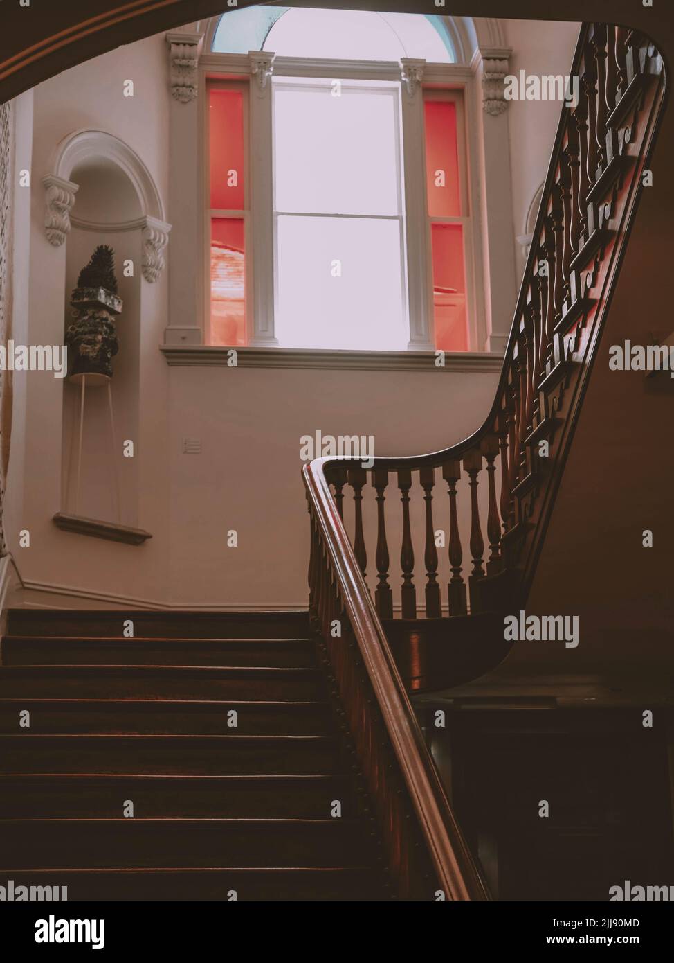 A vertical shot of a beautiful wooden stairway, stained glass window ...