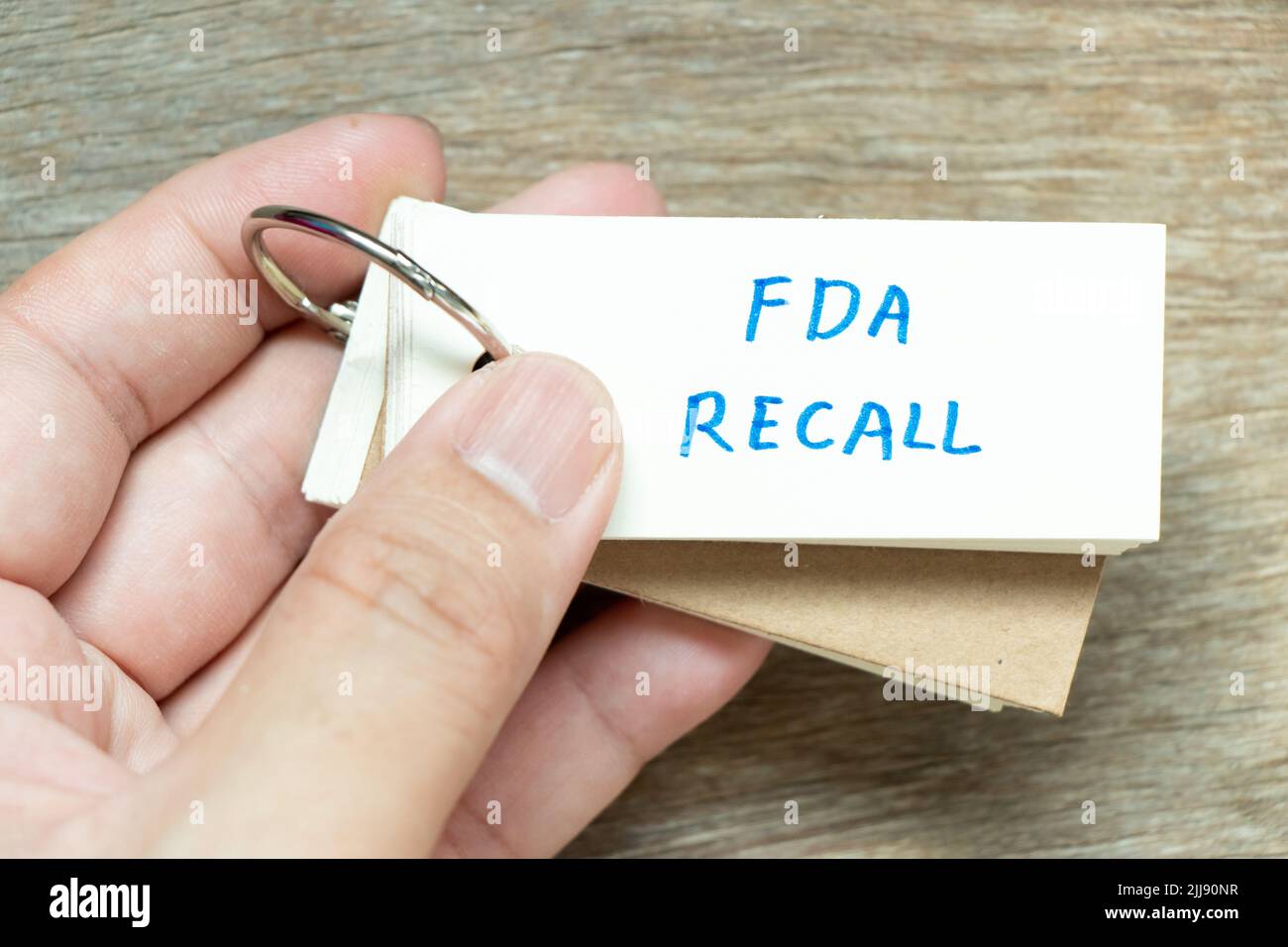Man hold the flash card with handwriting word FDA recall on wood ...