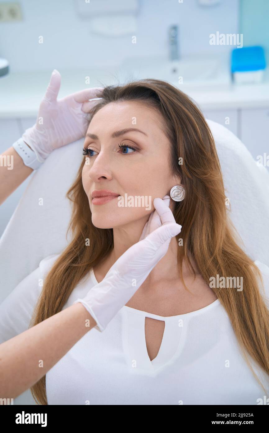 Female doctor examining lady face with both gloved hands Stock Photo ...