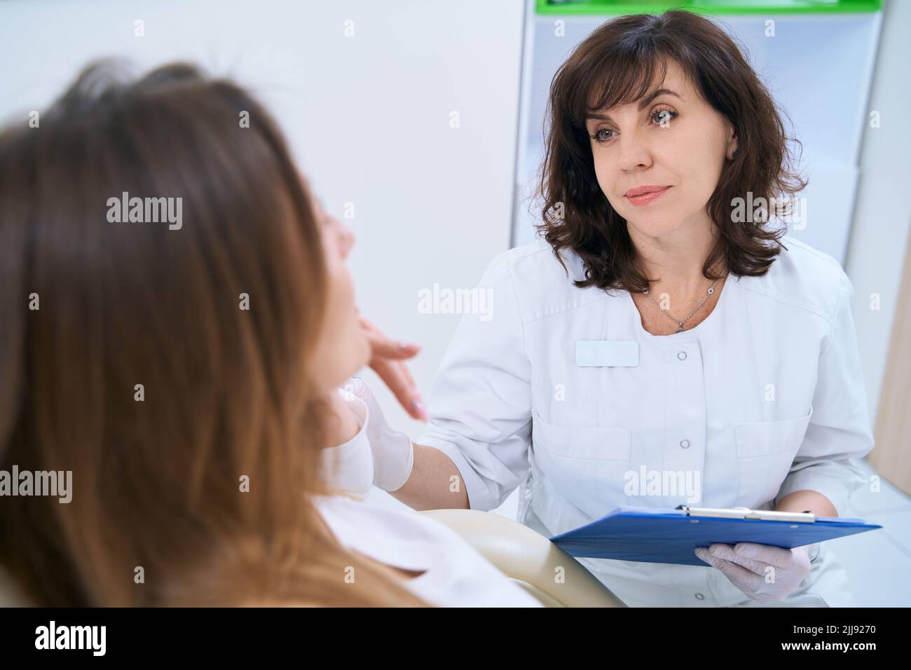 Dermatologist talking to a patient sitting in a chair Stock Photo - Alamy