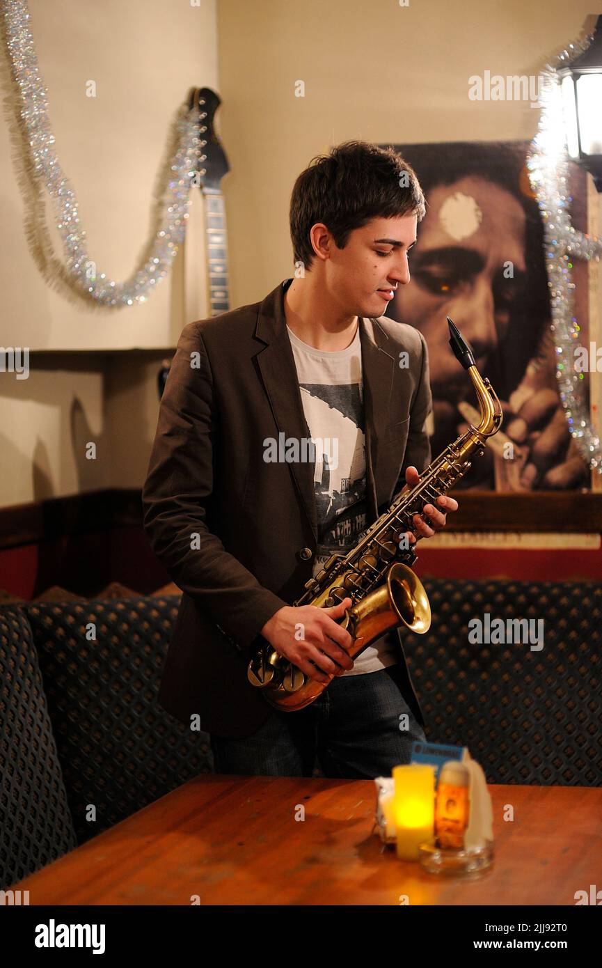 Young man musician playing saxophone at the small art cafe, photo of ...