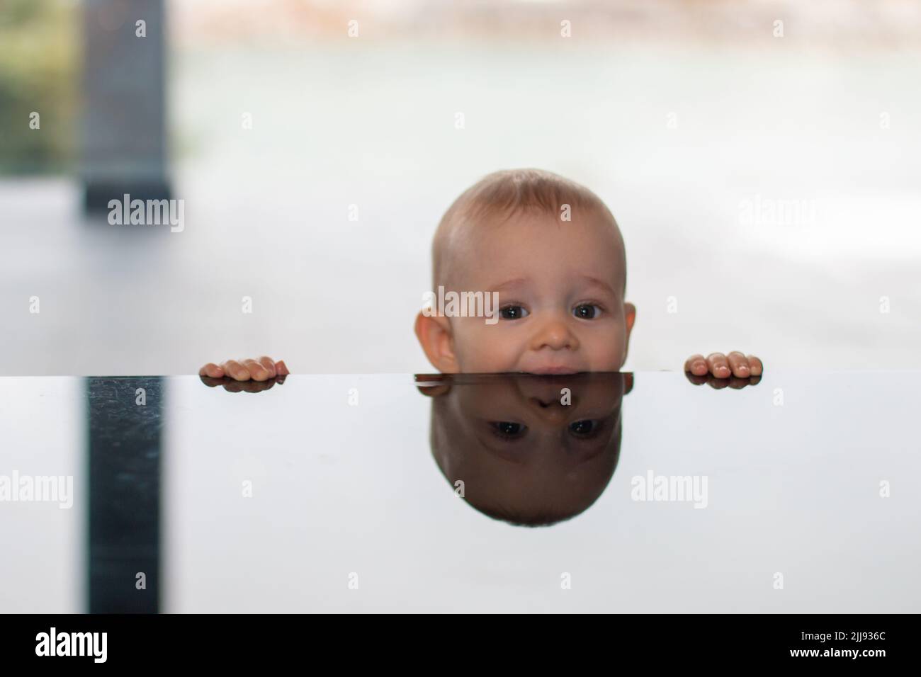 Cute toddler biting edge of a table, teething and exploring with head ...