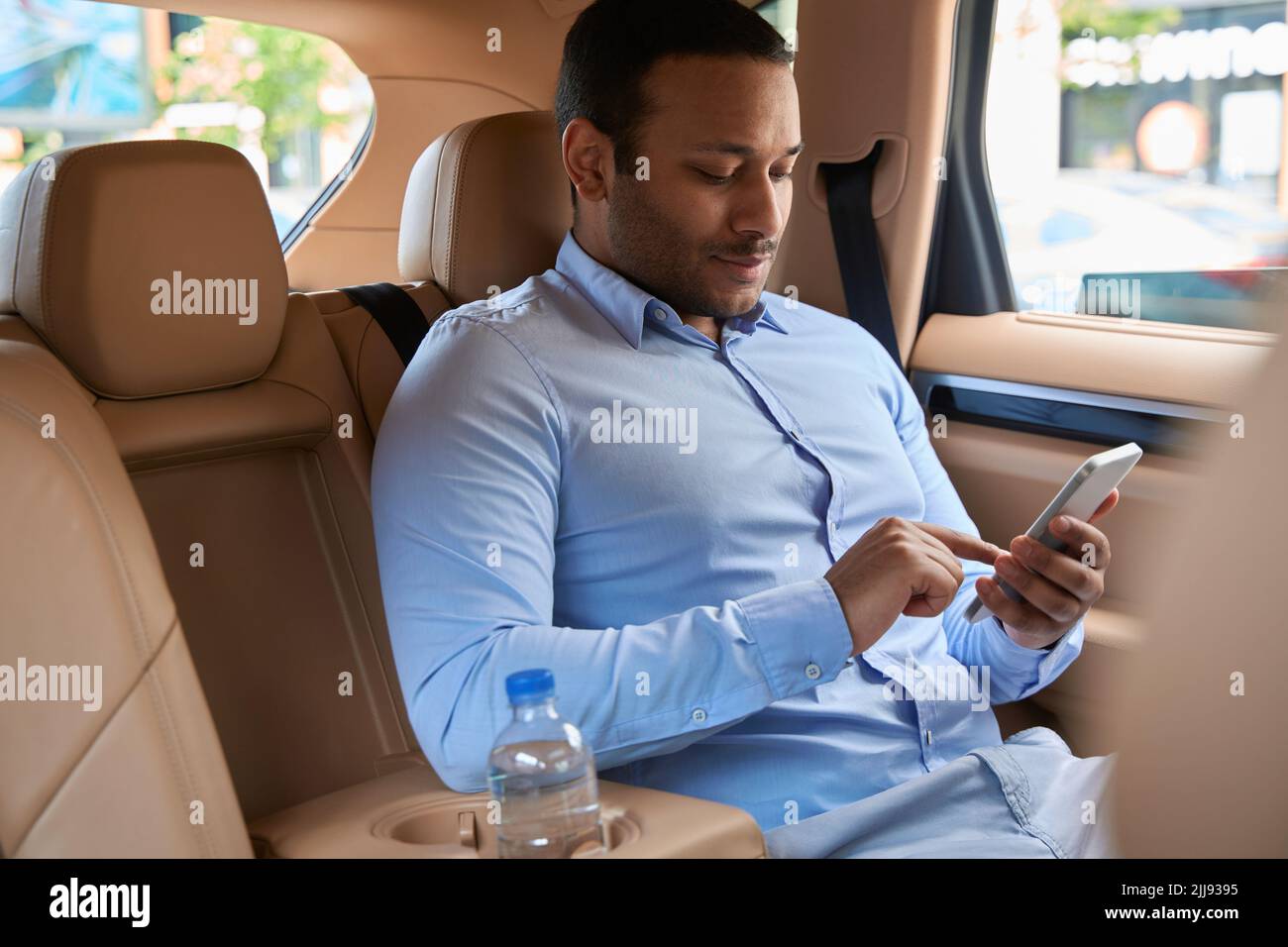 Passenger seated in auto using his cellphone Stock Photo - Alamy