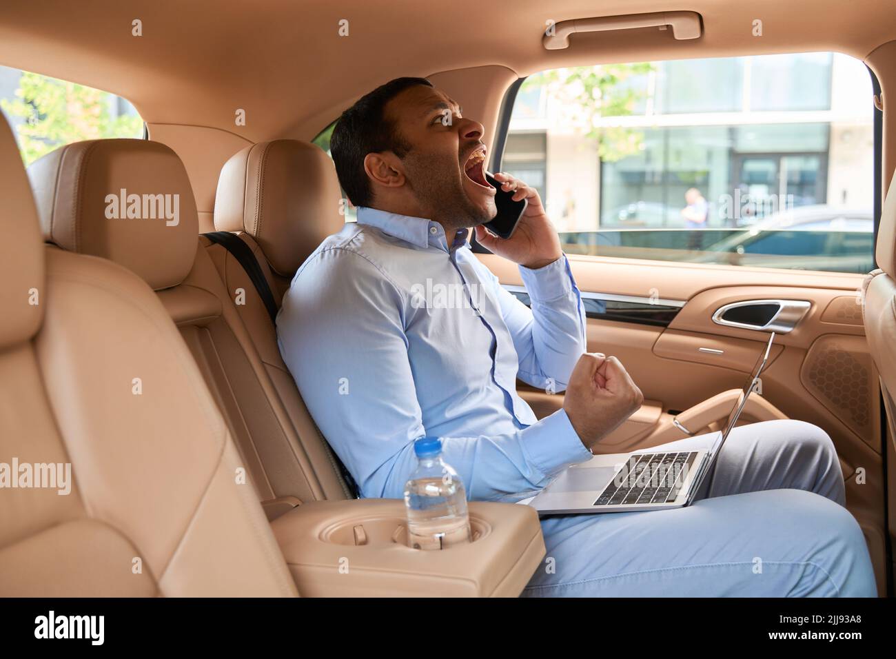 Delighted entrepreneur calling on smartphone in car Stock Photo - Alamy