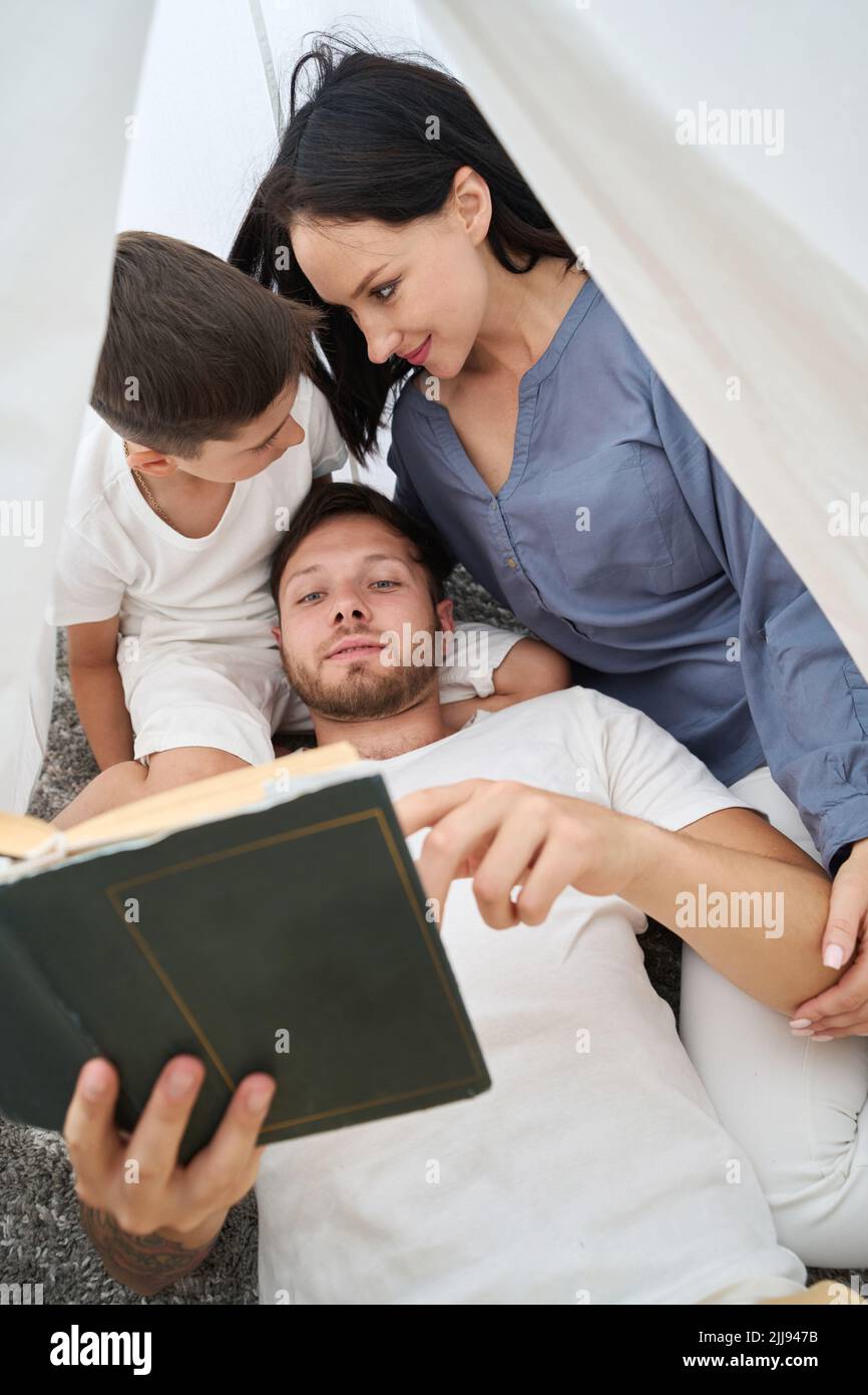 Family reading an evening fairy tale in cozy, magical hut Stock Photo ...