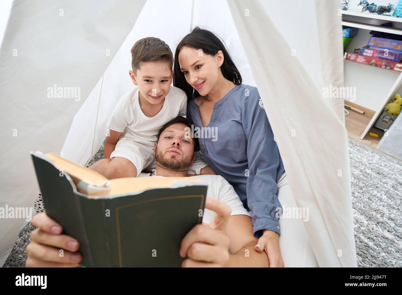 Family reading an evening fairy tale in cozy, magical hut Stock Photo ...