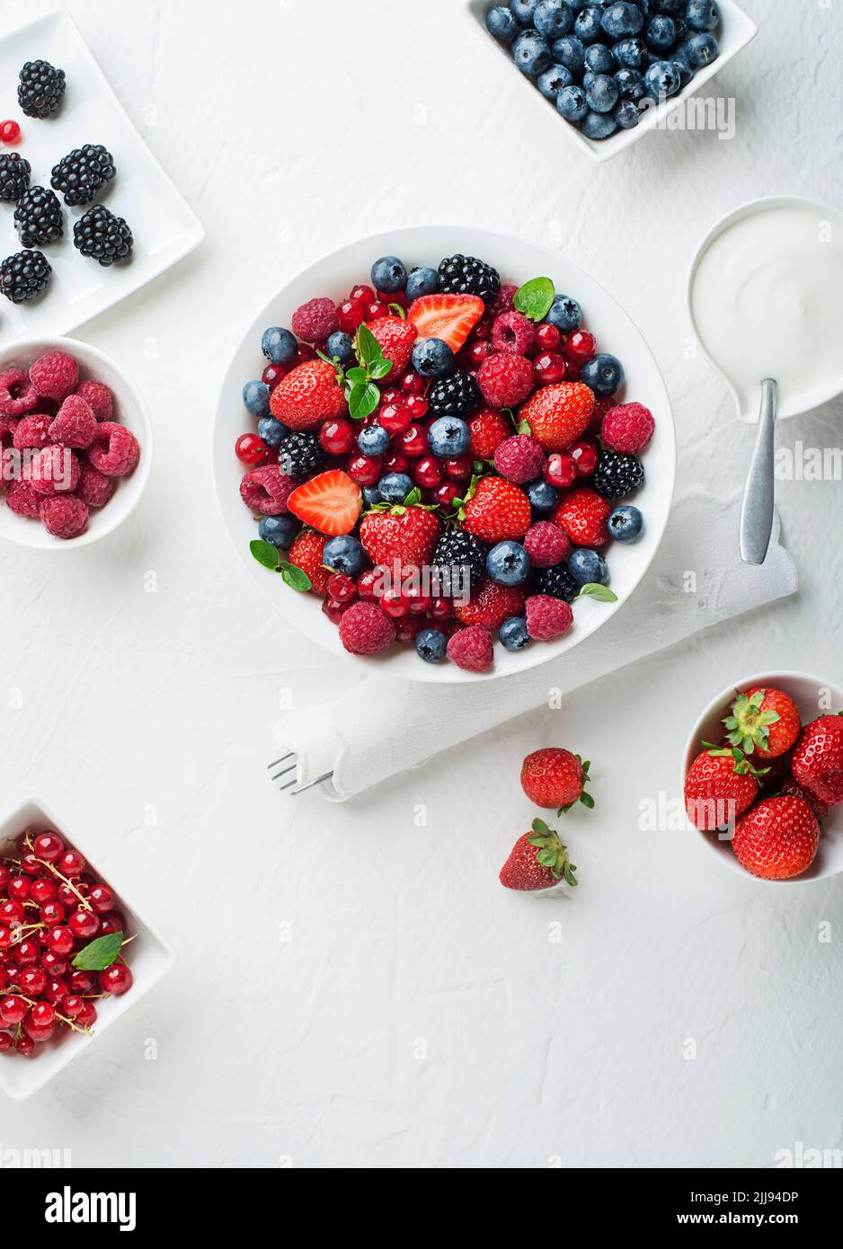 Bowl of healthy fresh berry fruit salad with cream on white background ...