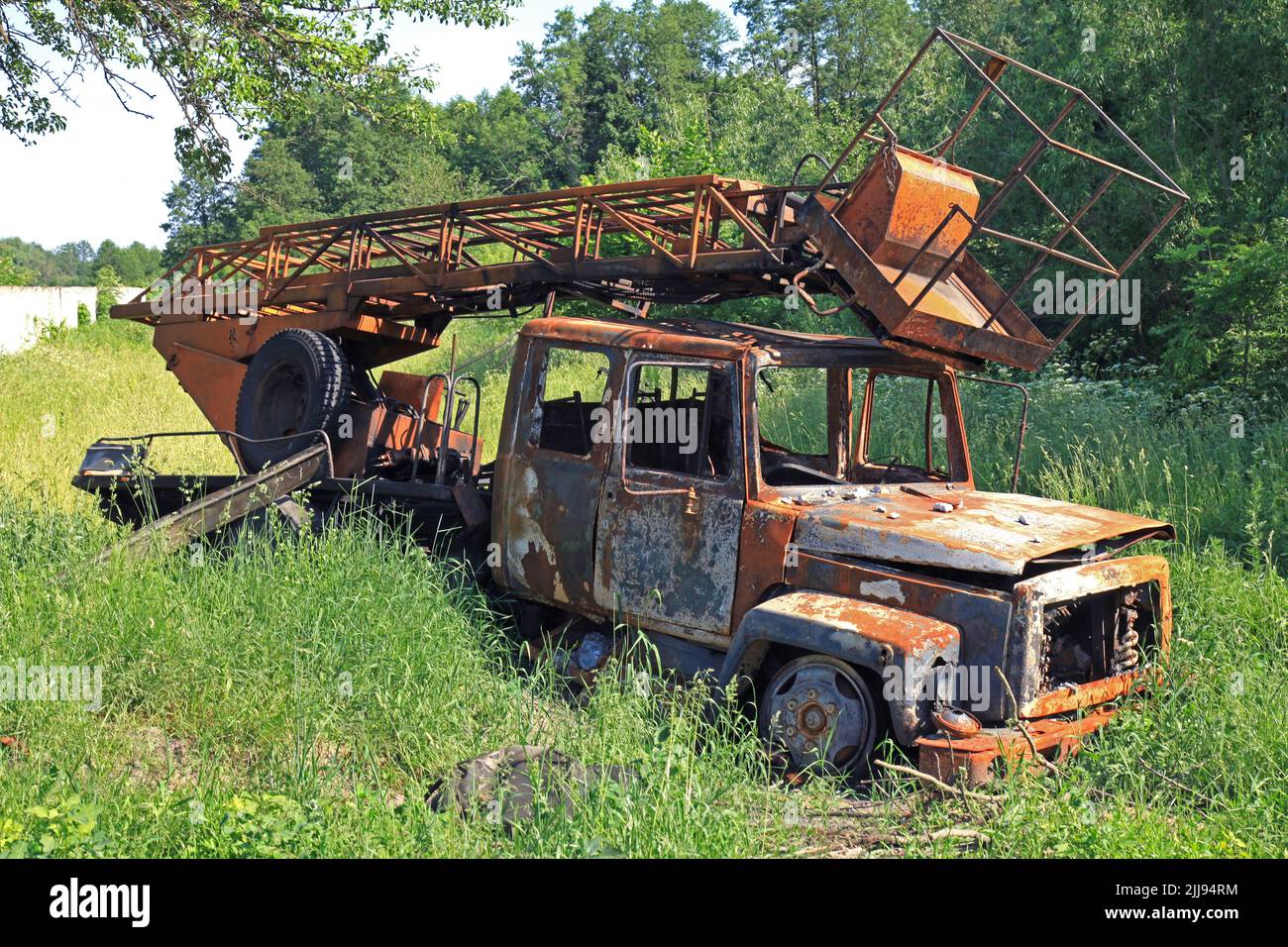 A charred truck on the side of the road in the green grass. A blown up ...