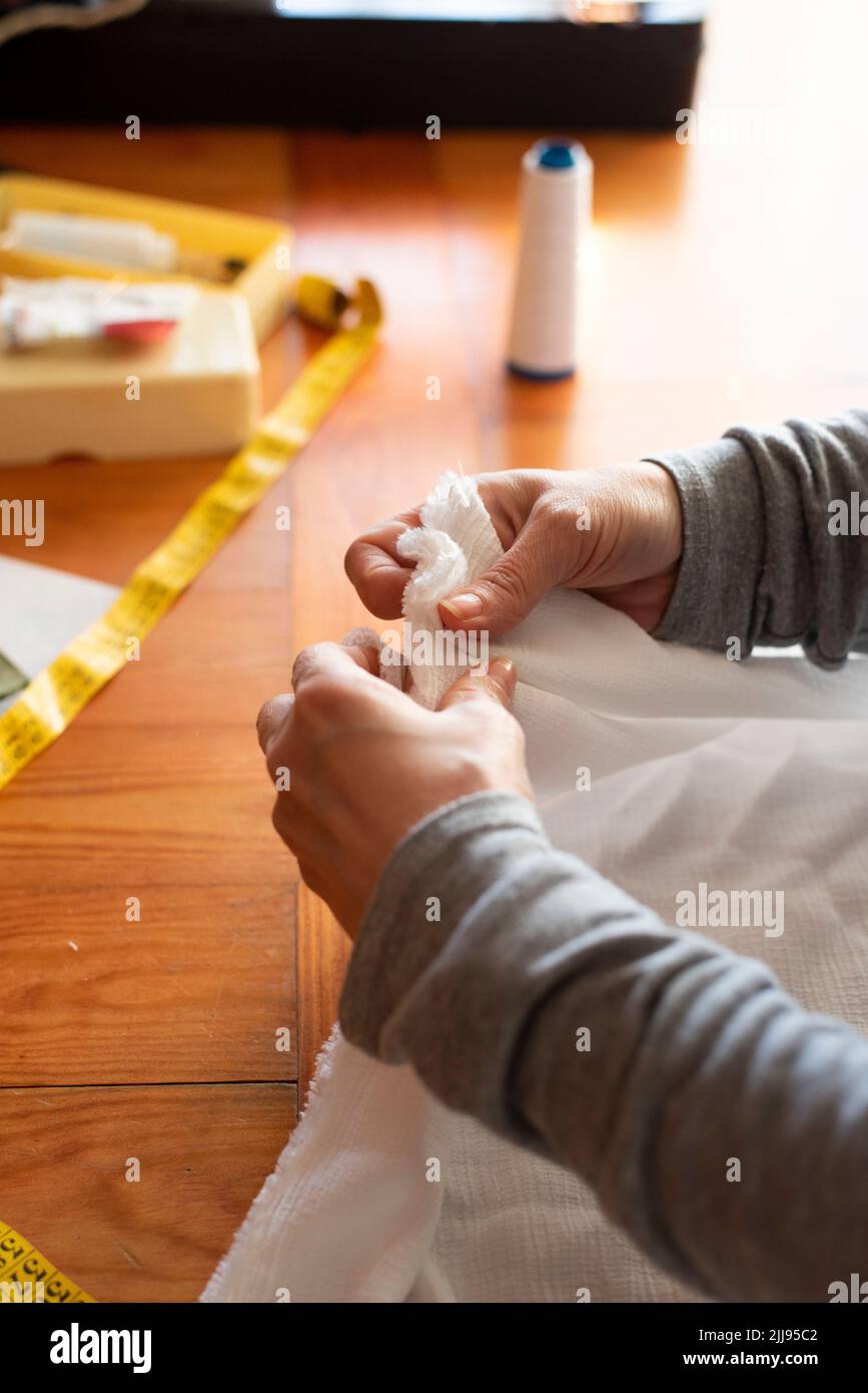 A female carefully sewing white cloth Stock Photo - Alamy