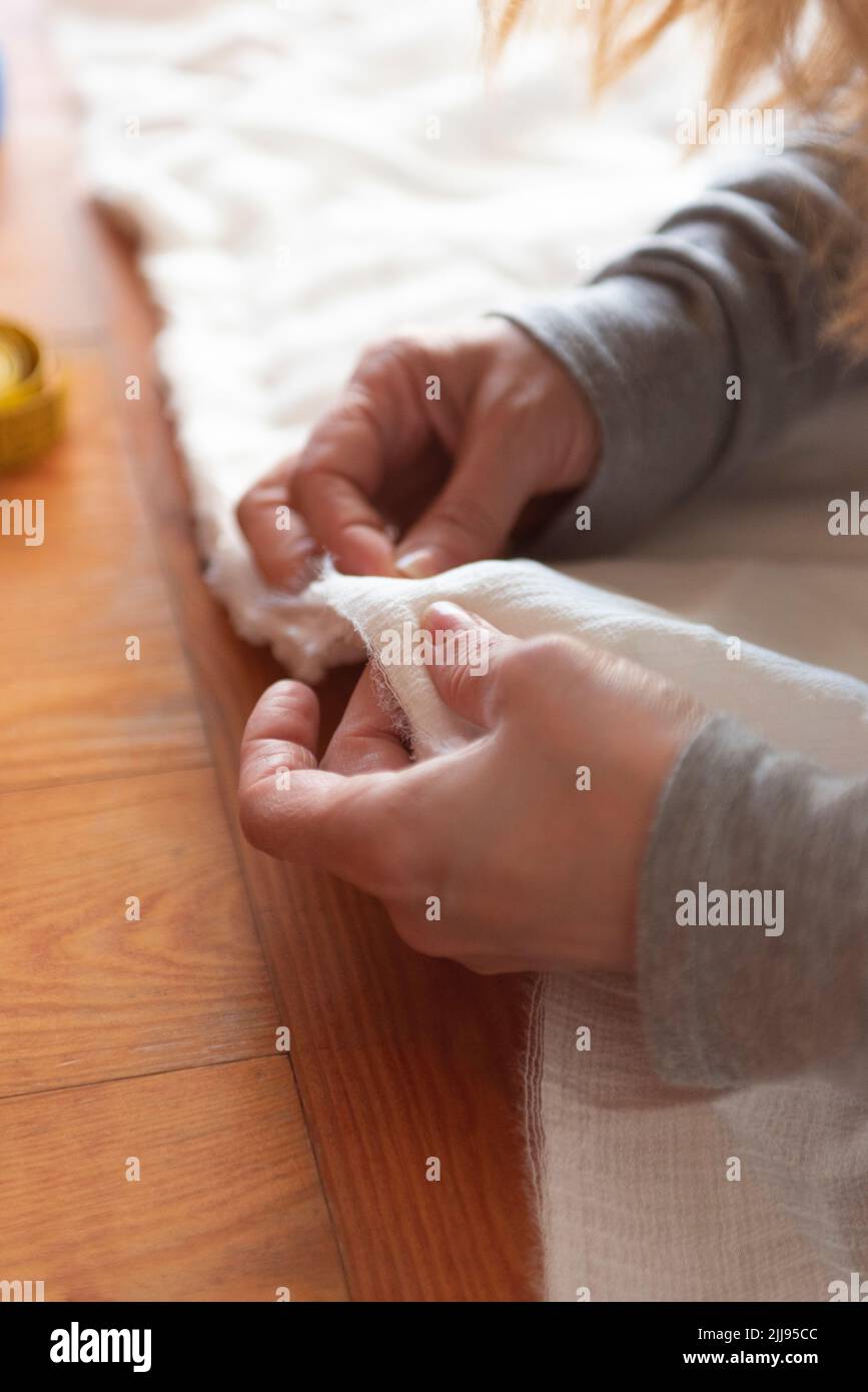 A female carefully sewing white cloth Stock Photo - Alamy