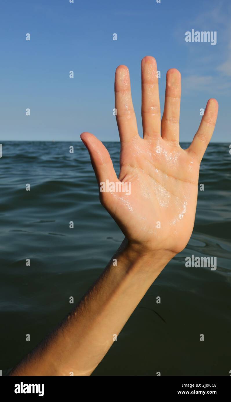 large hand with five fingers sticking out of the surface of the sea ...