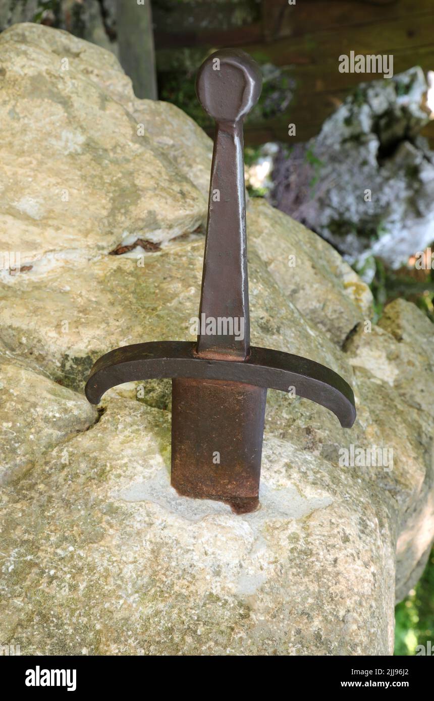 sword set in the stone in the middle of the forest of trees symbol of ...