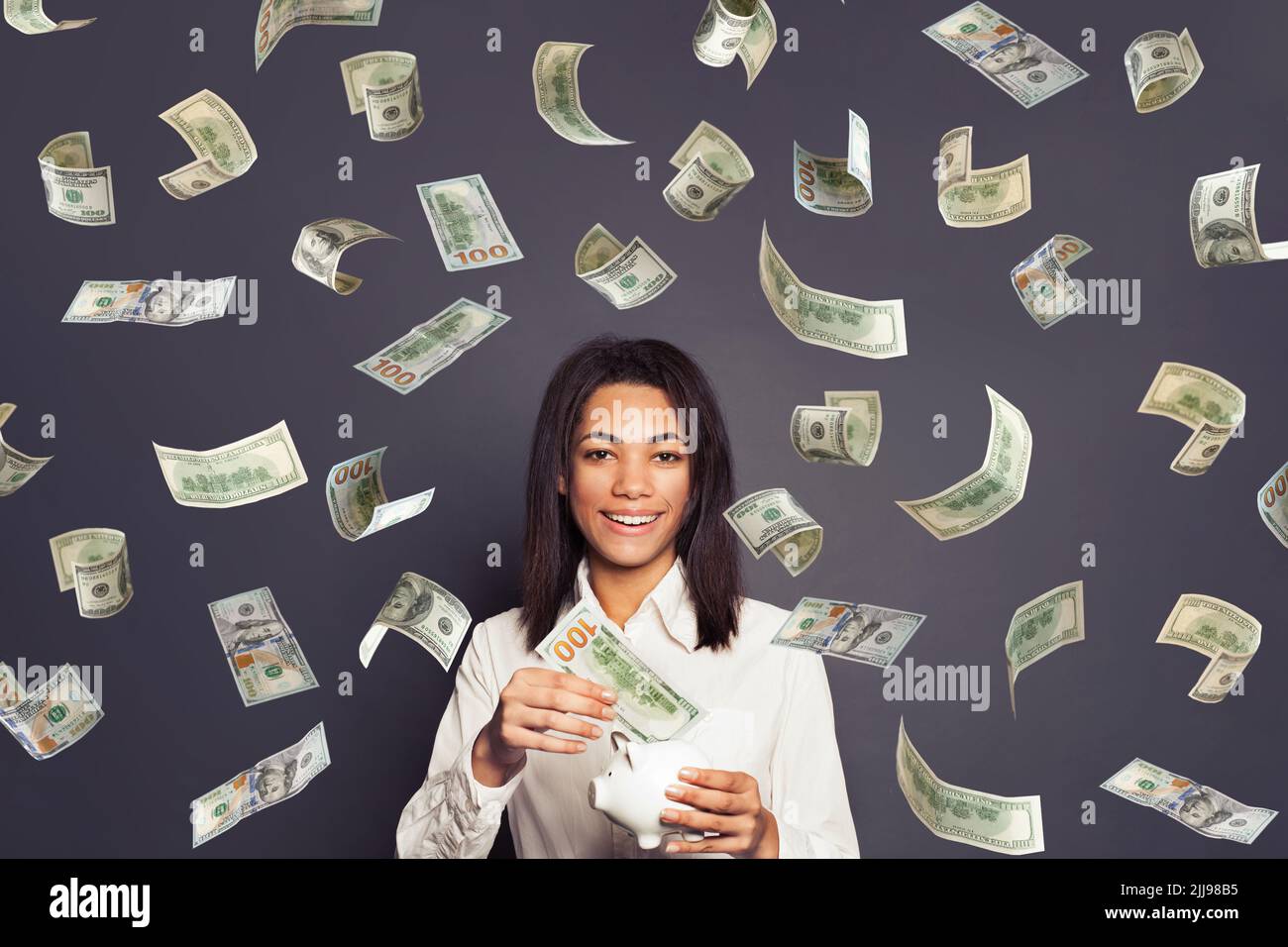 Happy african american woman smiling and holding white piggy bank in ...