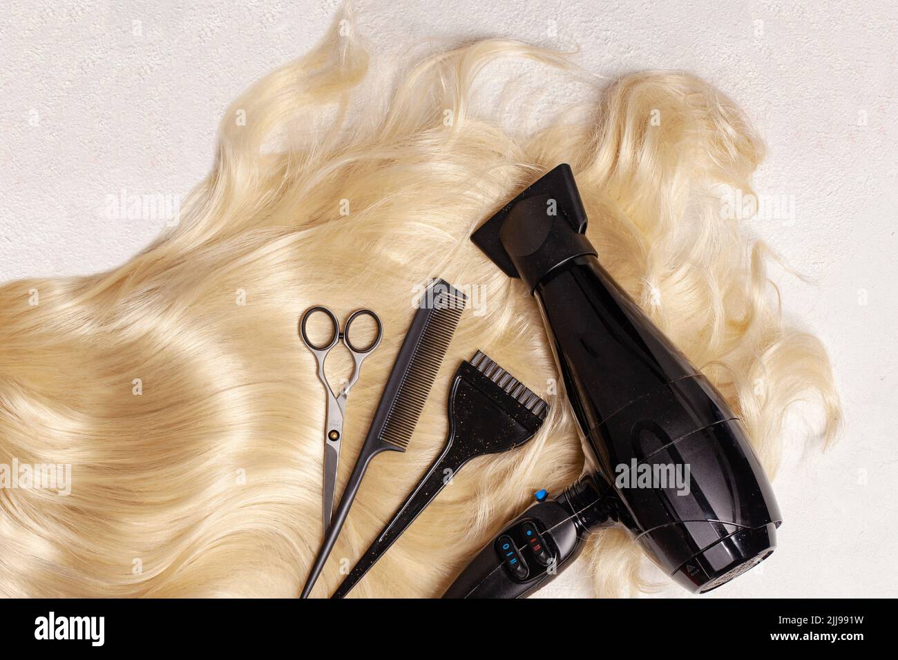 Hair dryer, scissors, comb and brush on blonde hair. Hairdresser salon ...