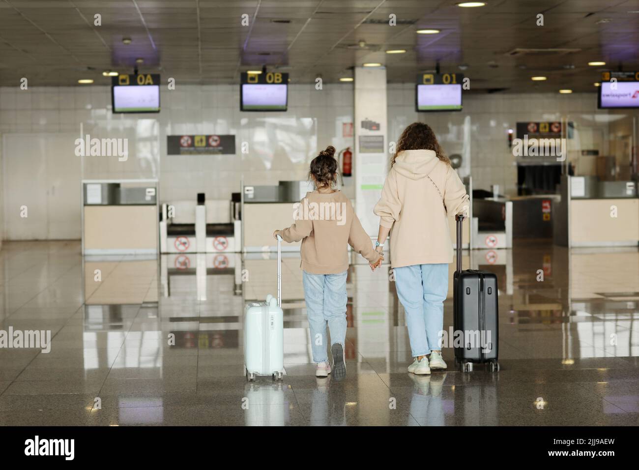 Family at airport before flight. back view of mother with daughter with ...