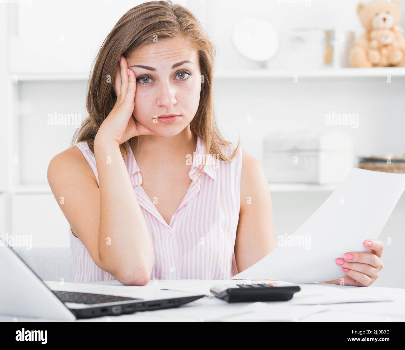Young woman looking worriedly at bills Stock Photo - Alamy