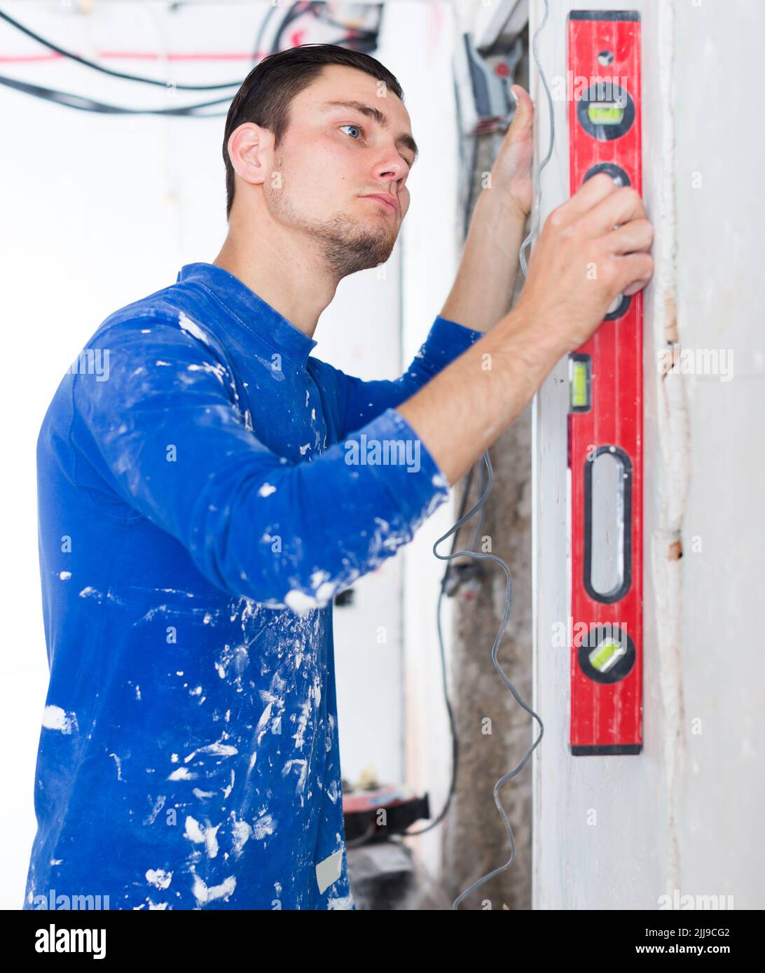Handyman measuring angle of wall with level Stock Photo - Alamy