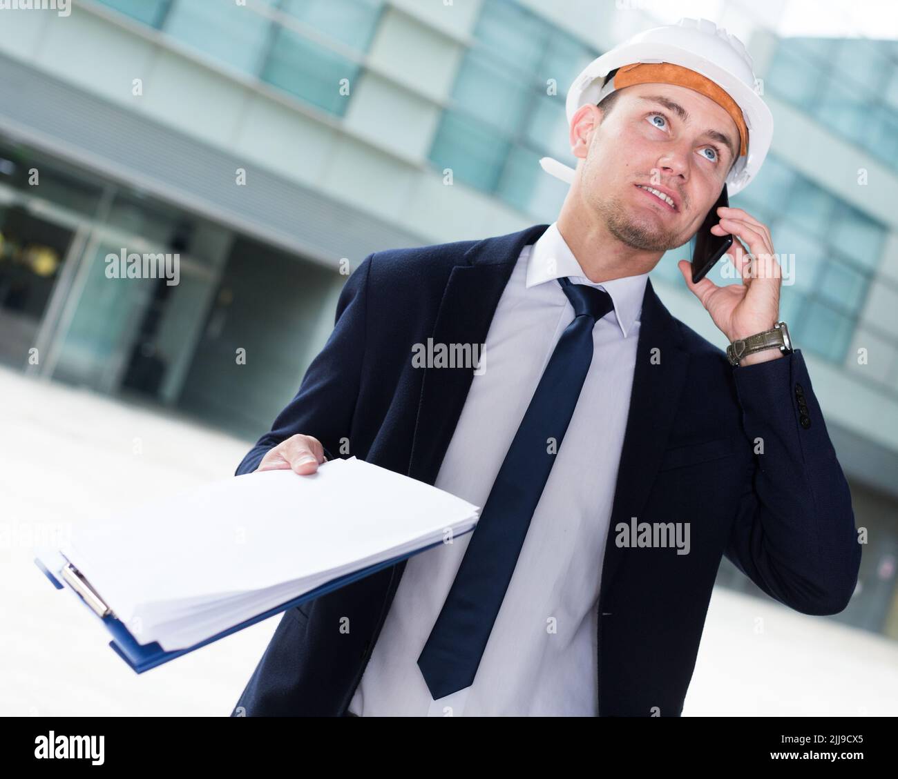 Engineer in suit and hat is taking document case and considering ...
