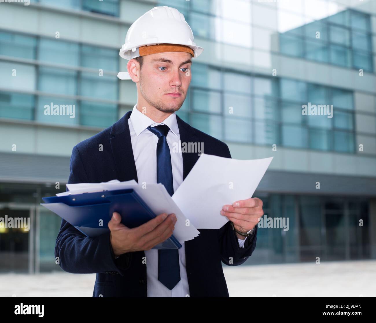 Designer in suit and hat with folder is looking into documents with ...