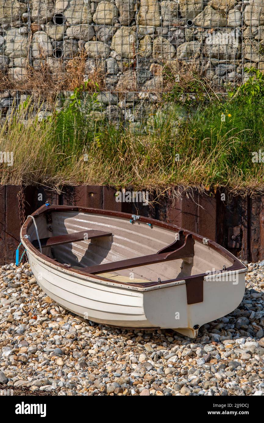 small rowing boat or dinghy on a beach high and dry washed up on the ...